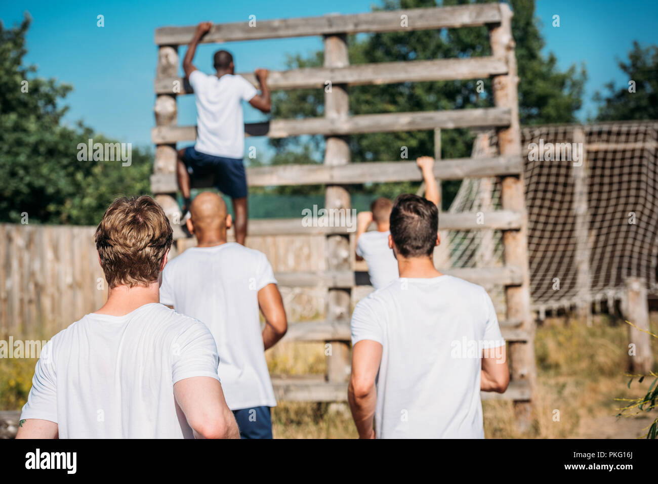 back view of multicultural soldiers practicing obstacle run on range on ...