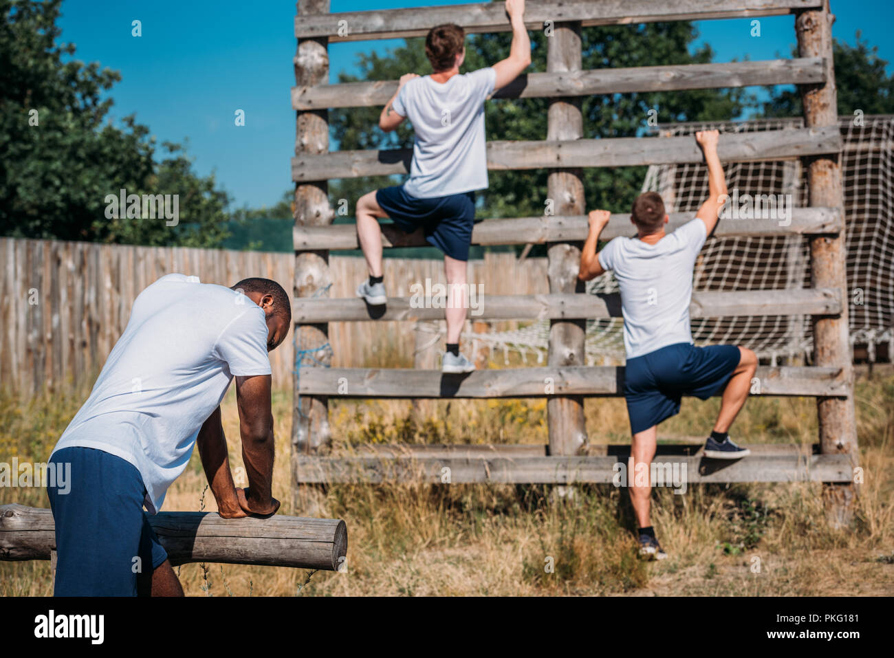 back view of multicultural soldiers practicing obstacle run on range on ...