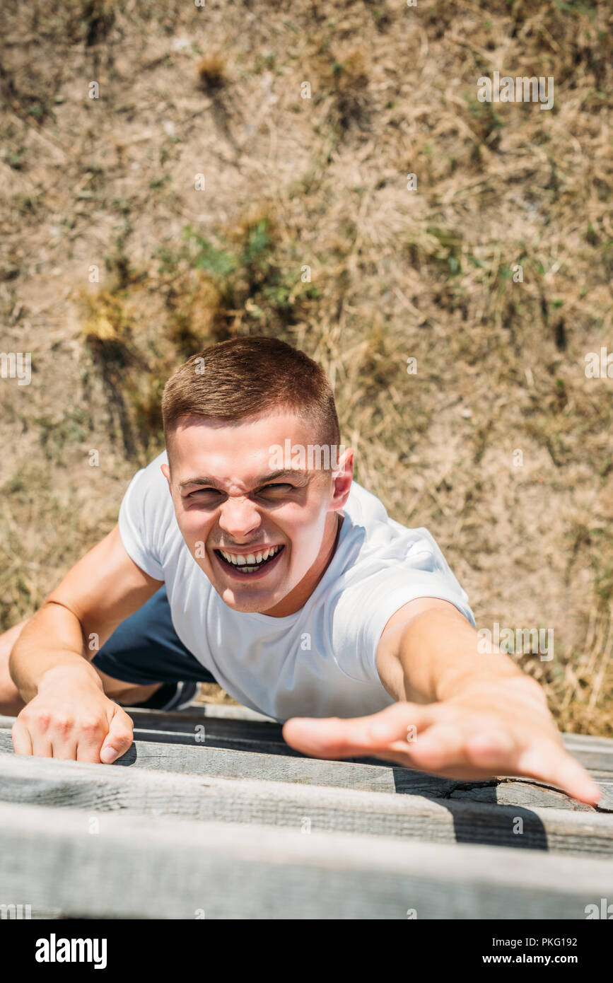 overhead view of young soldier climbing wooden barrier during obstacle ...