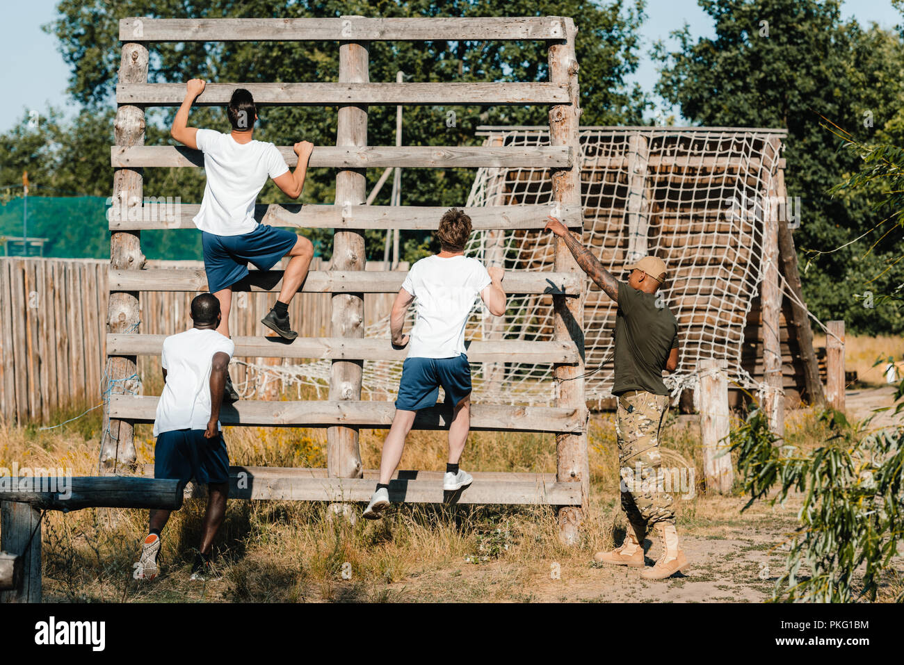 tactical instructor examining multiracial soldiers during obstacle run ...