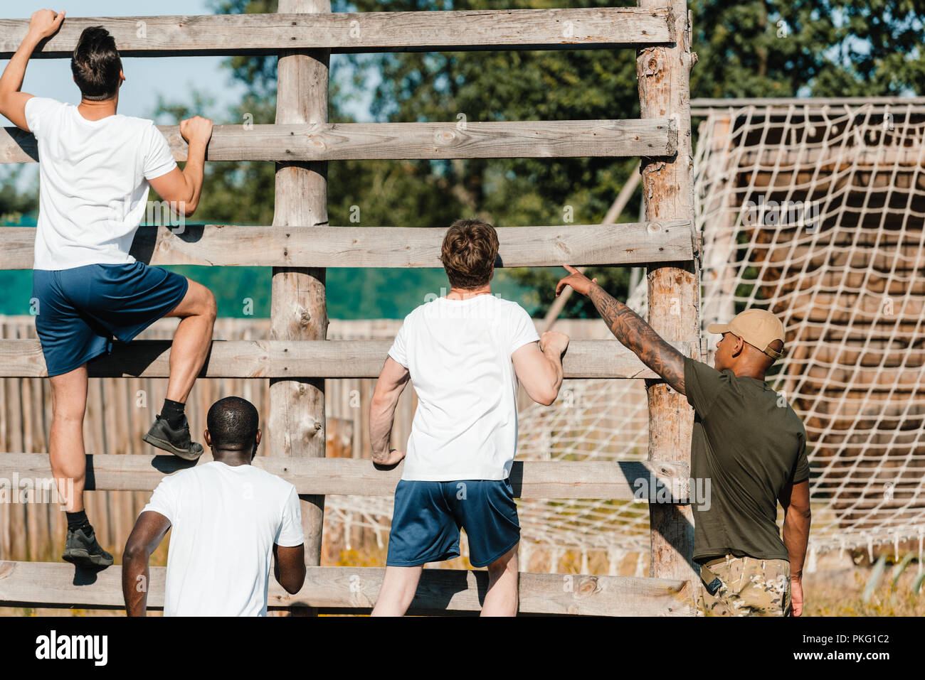 tactical instructor examining multiracial soldiers during obstacle run ...