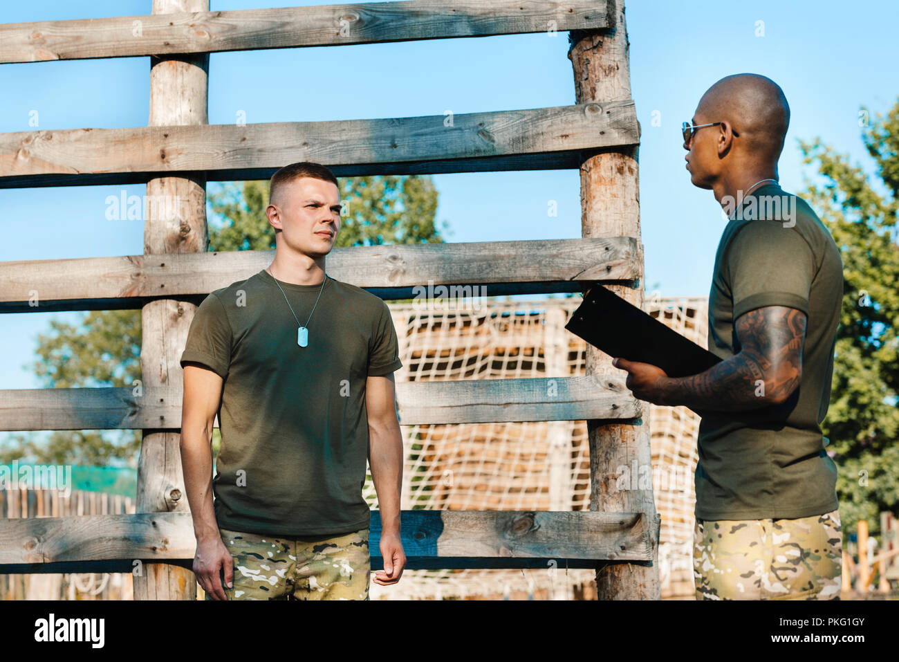african american tactical instructor with notepad and young soldier in ...