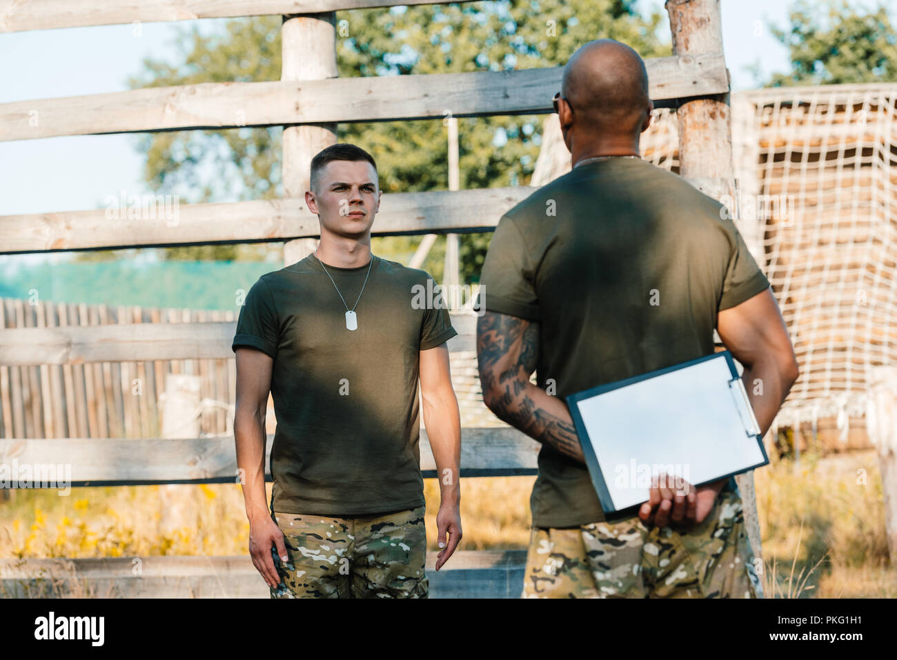 african american tactical instructor with notepad and young soldier in ...