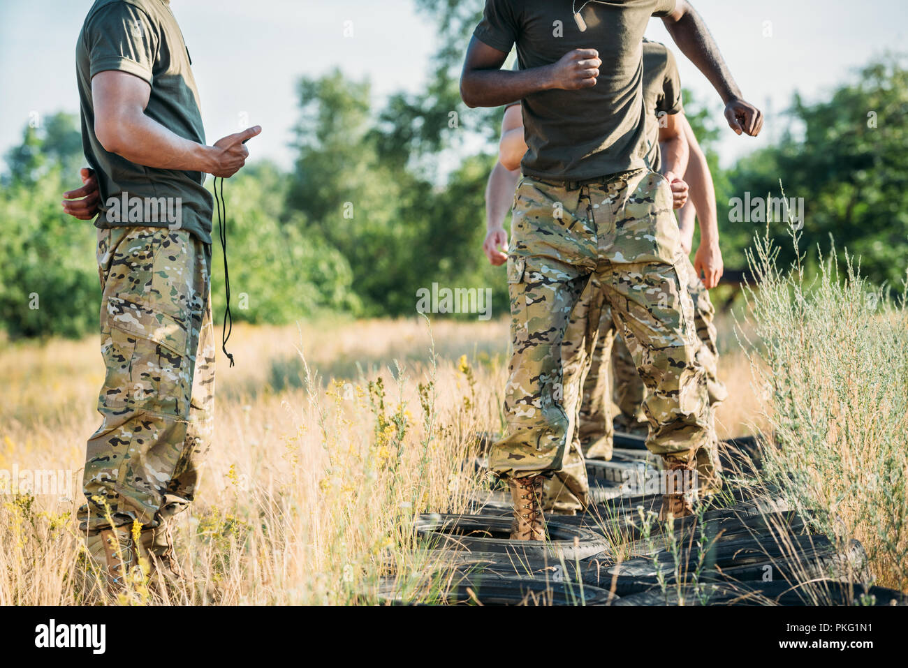 partial view of tactical instructor with stop watch and interracial ...