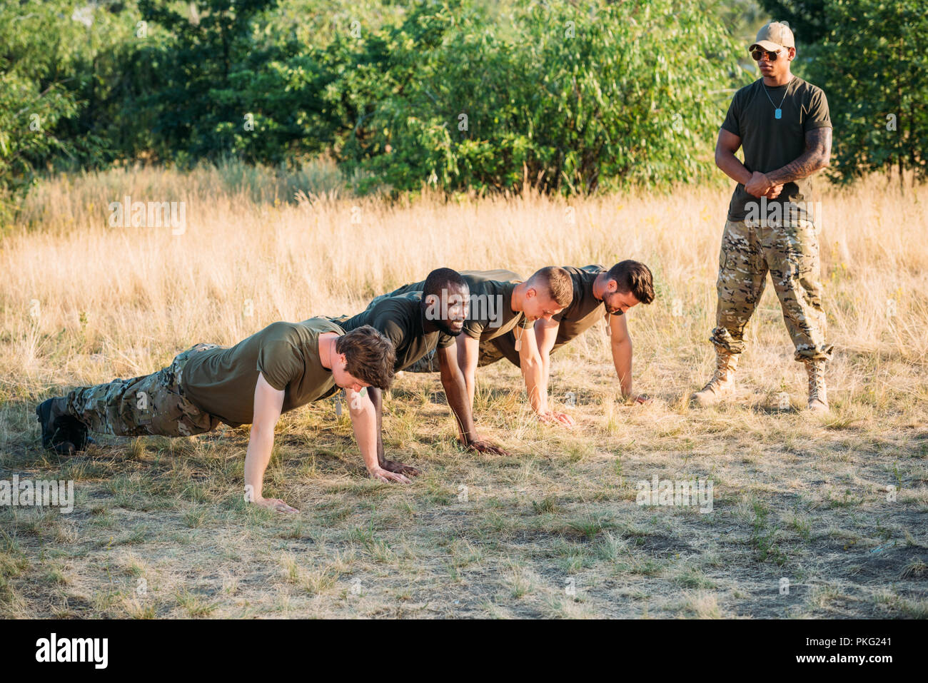 tactical instructor in sunglasses examining multicultural soldiers ...