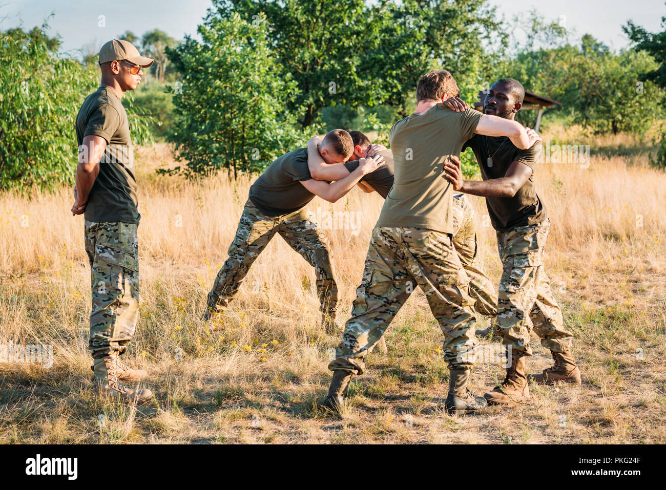 multiracial soldiers in military uniform practicing hand to hand ...