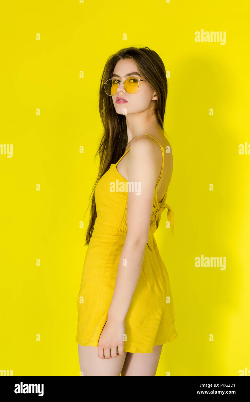 Female fashion model in yellow dress and sunglasses posing on yellow ...