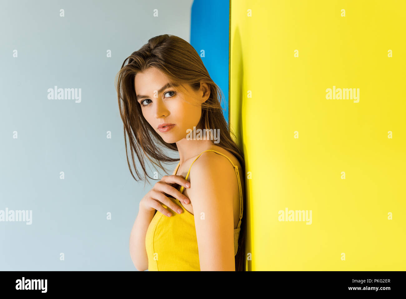 Female fashion model in yellow clothes on blue and yellow background ...
