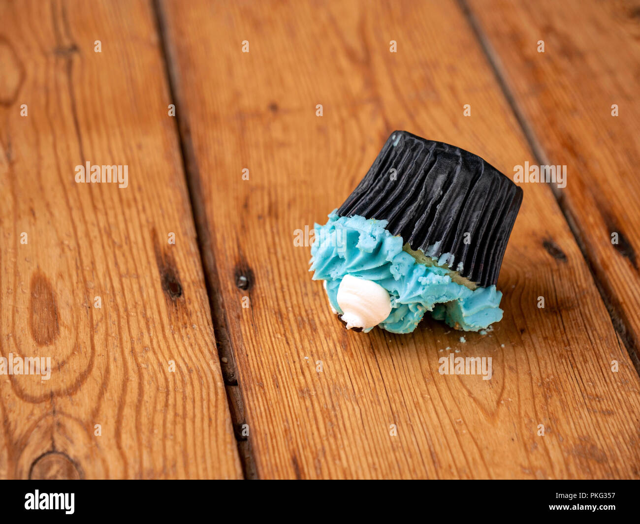A cupcake with blue icing that has been dropped upside down onto a ...