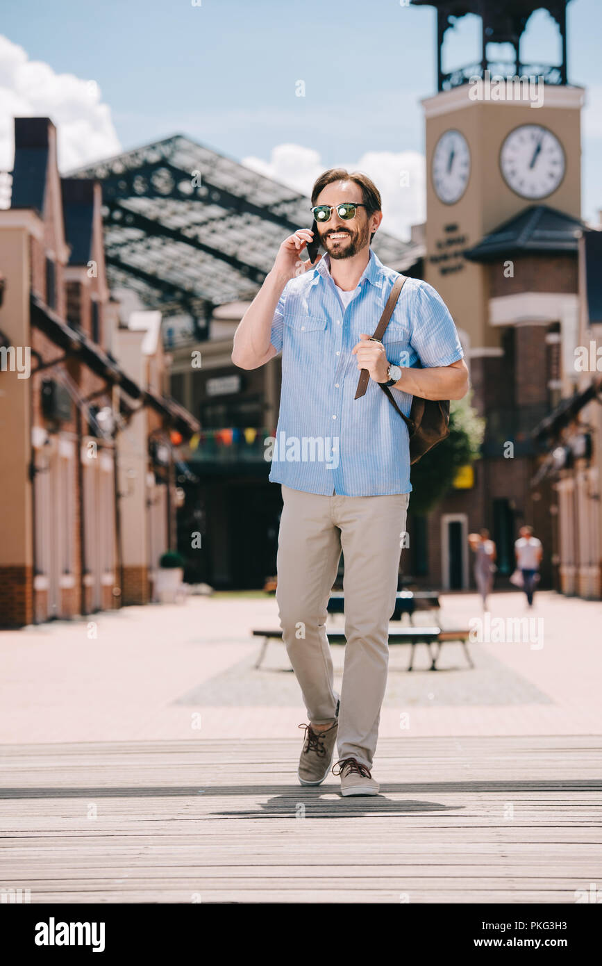 handsome man talking by smartphone and walking on street Stock Photo ...