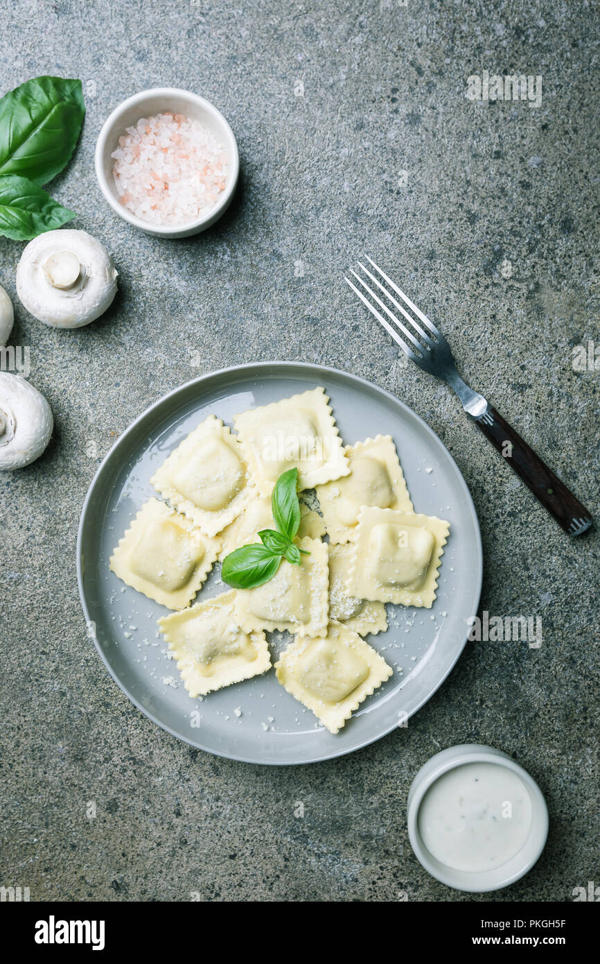 Plate of ravioli with mushrooms and cheese decorated by basil on dark ...