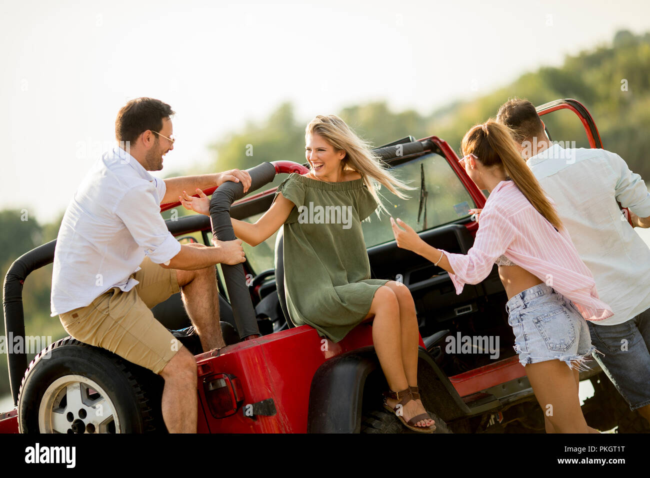 Four young people having fun in convertible car by river Stock Photo ...