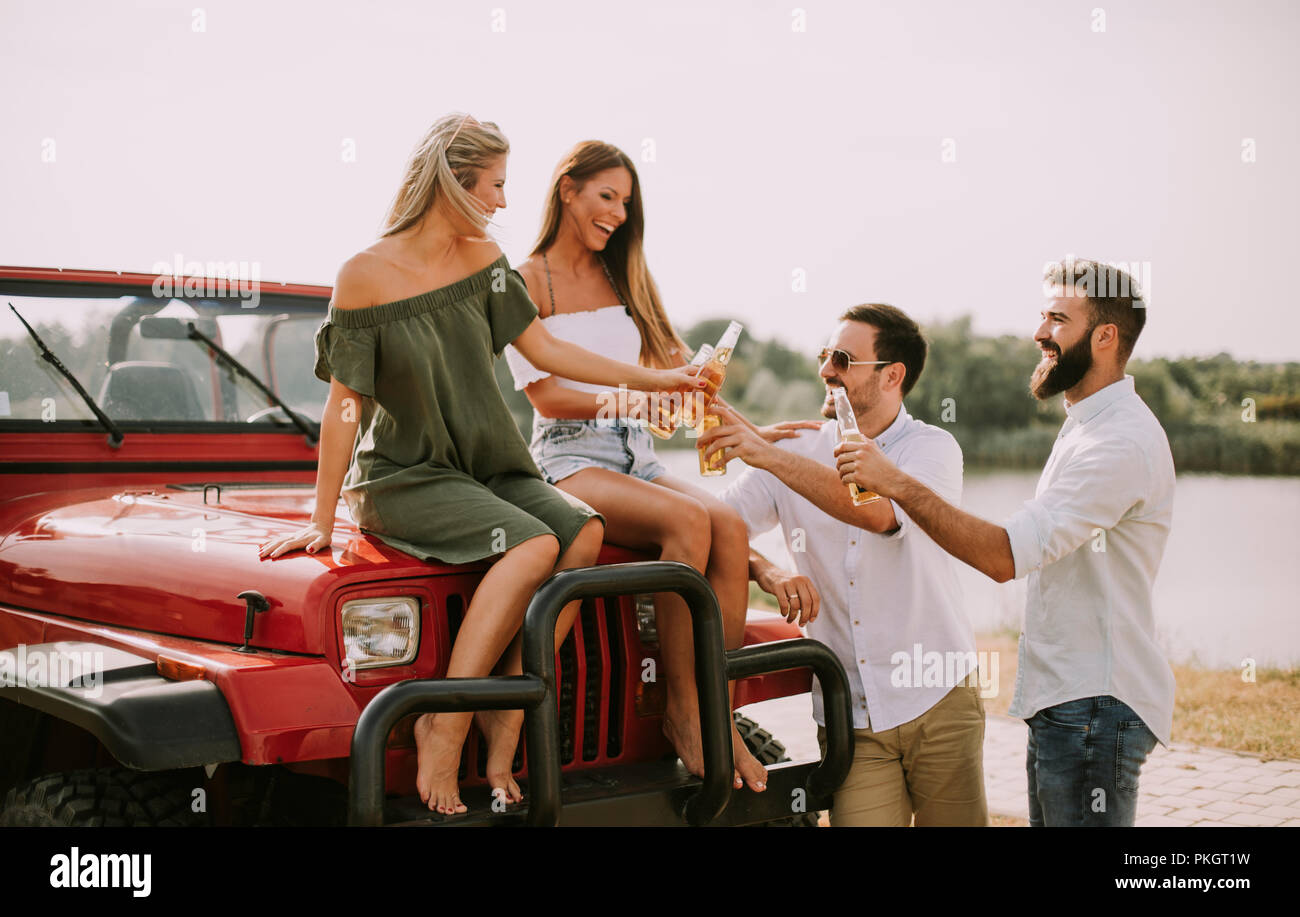 Young people drinking and having fun by car outdoor at hot summer day ...