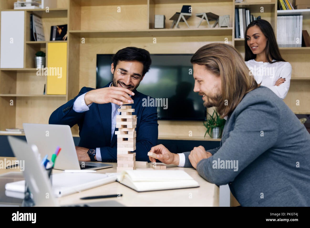Team of young business people build a wooden construction in the office ...