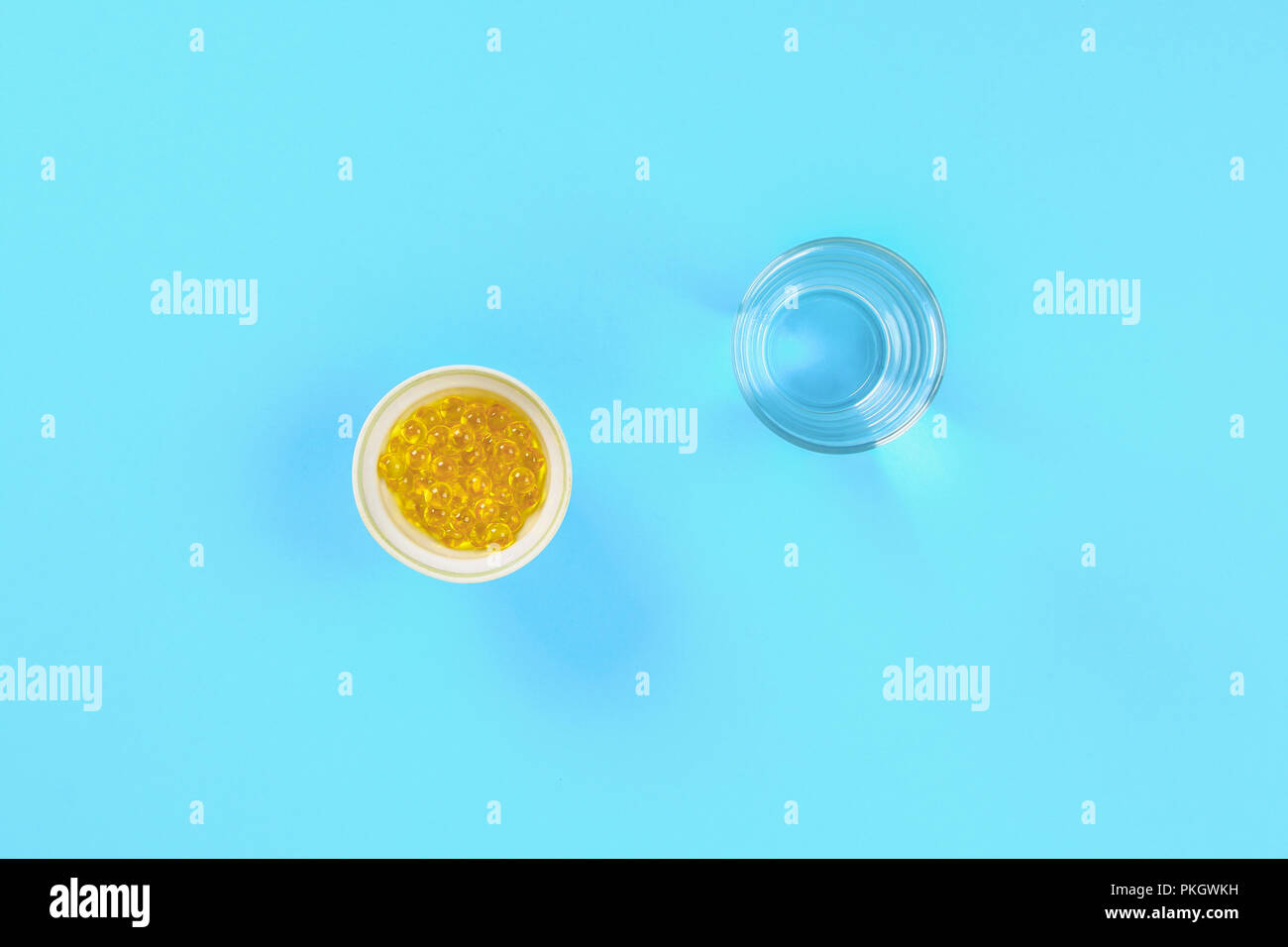 Swallowing tablets. Pills and a glass of water against a blue table ...