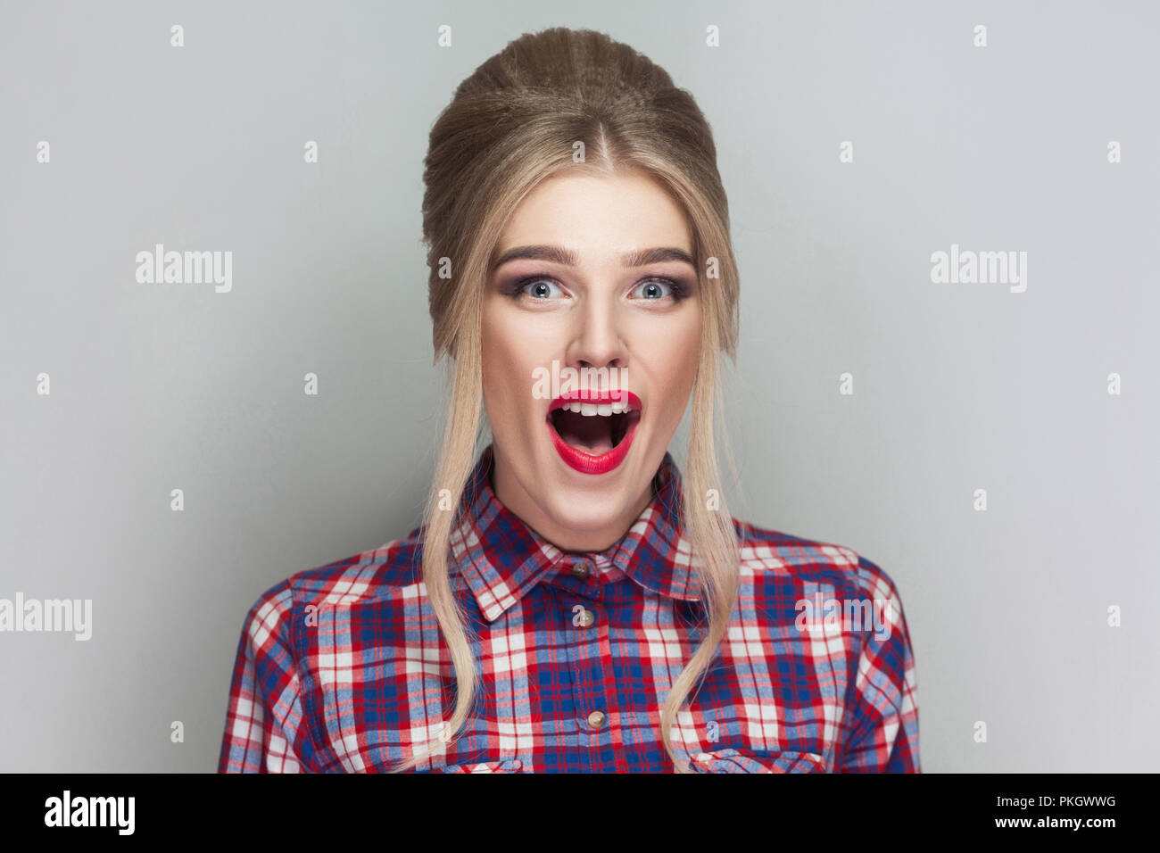 Amazed beautiful blonde girl with pink checkered shirt, collected updo ...
