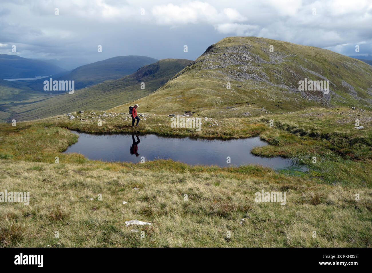 Reflection in a Lochan of Man Walking on the Scottish Mountain Corbett ...