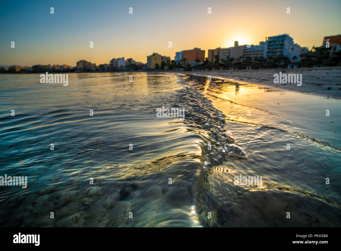 Wavy curves of sea is covered in golden sunset light. Sea at sunset ...