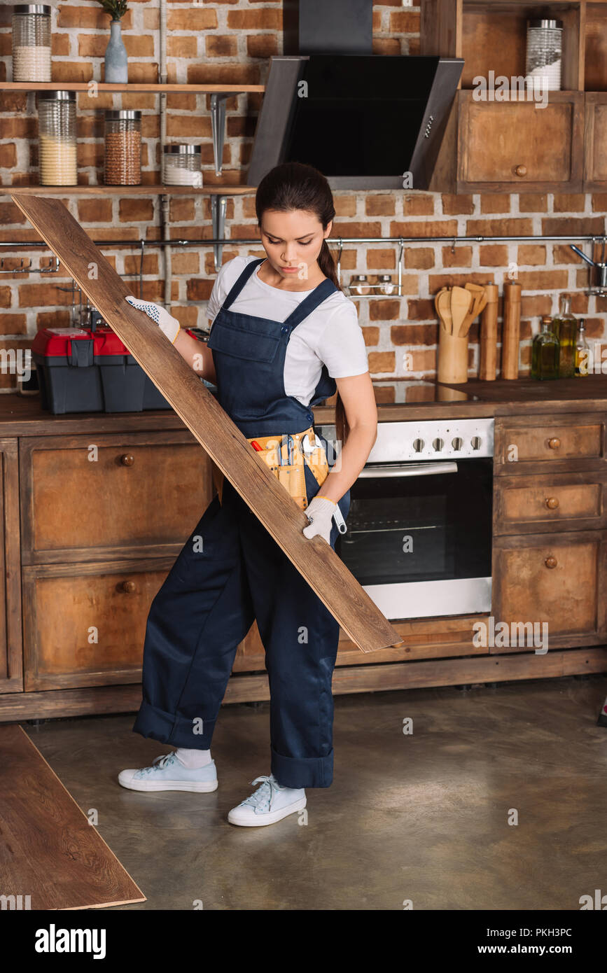 attractive young repairwoman installing laminate onto kitchen floor ...