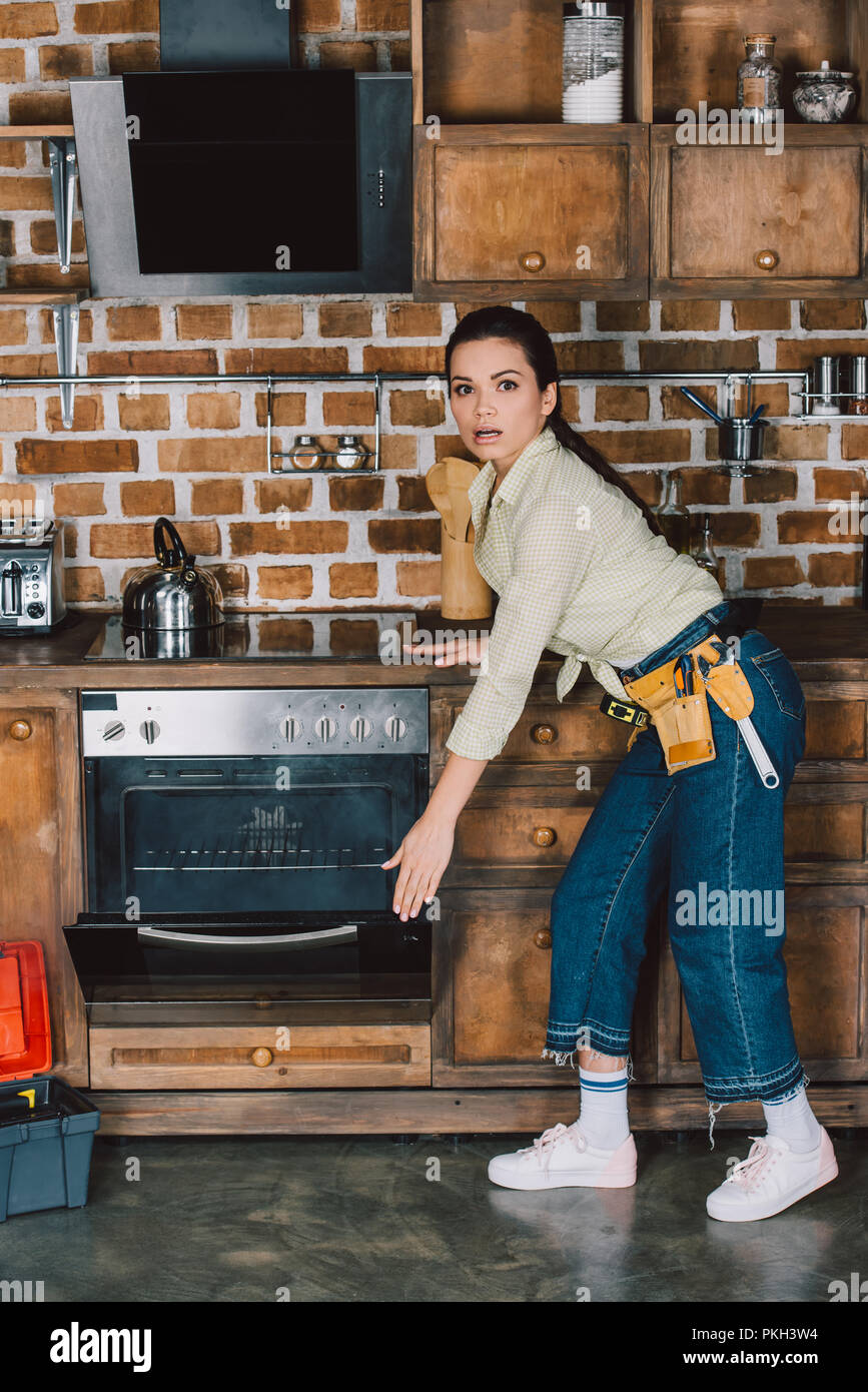 shocked young repairwoman opening broken oven with smoke inside Stock ...