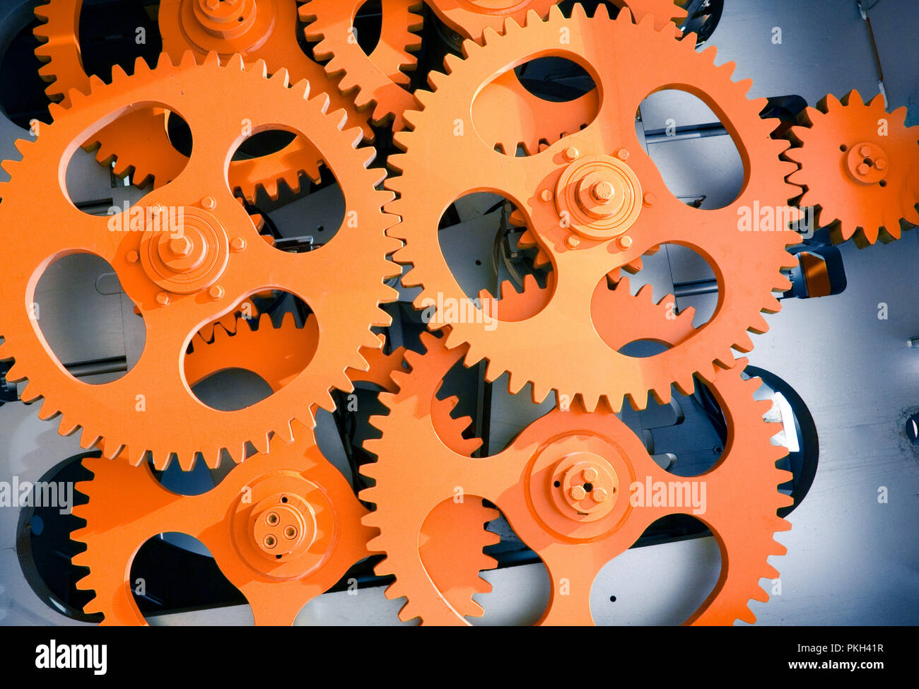 Interaction of orange gears in machine Stock Photo - Alamy
