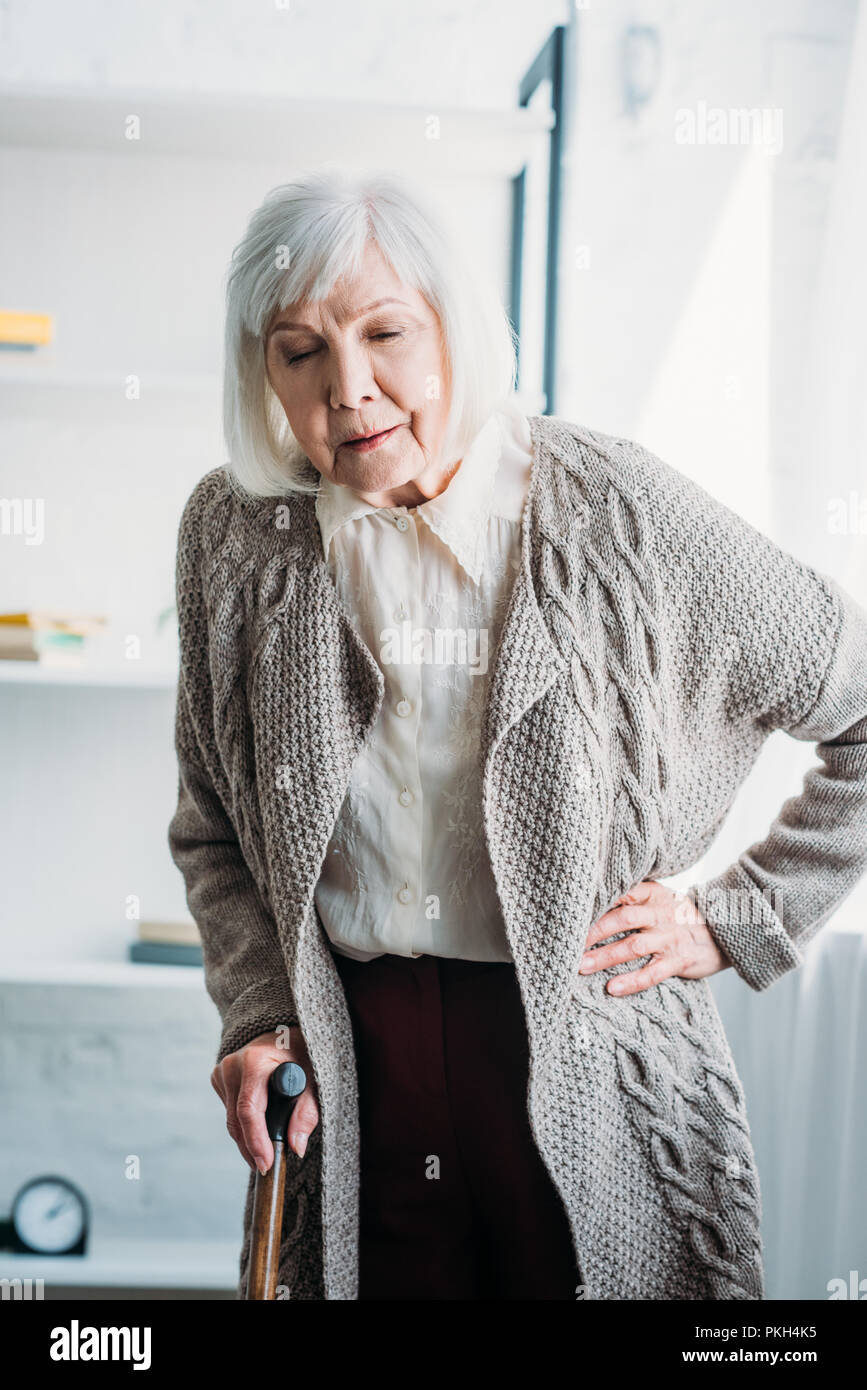 portrait of grey hair lady akimbo with wooden walking stick standing in ...