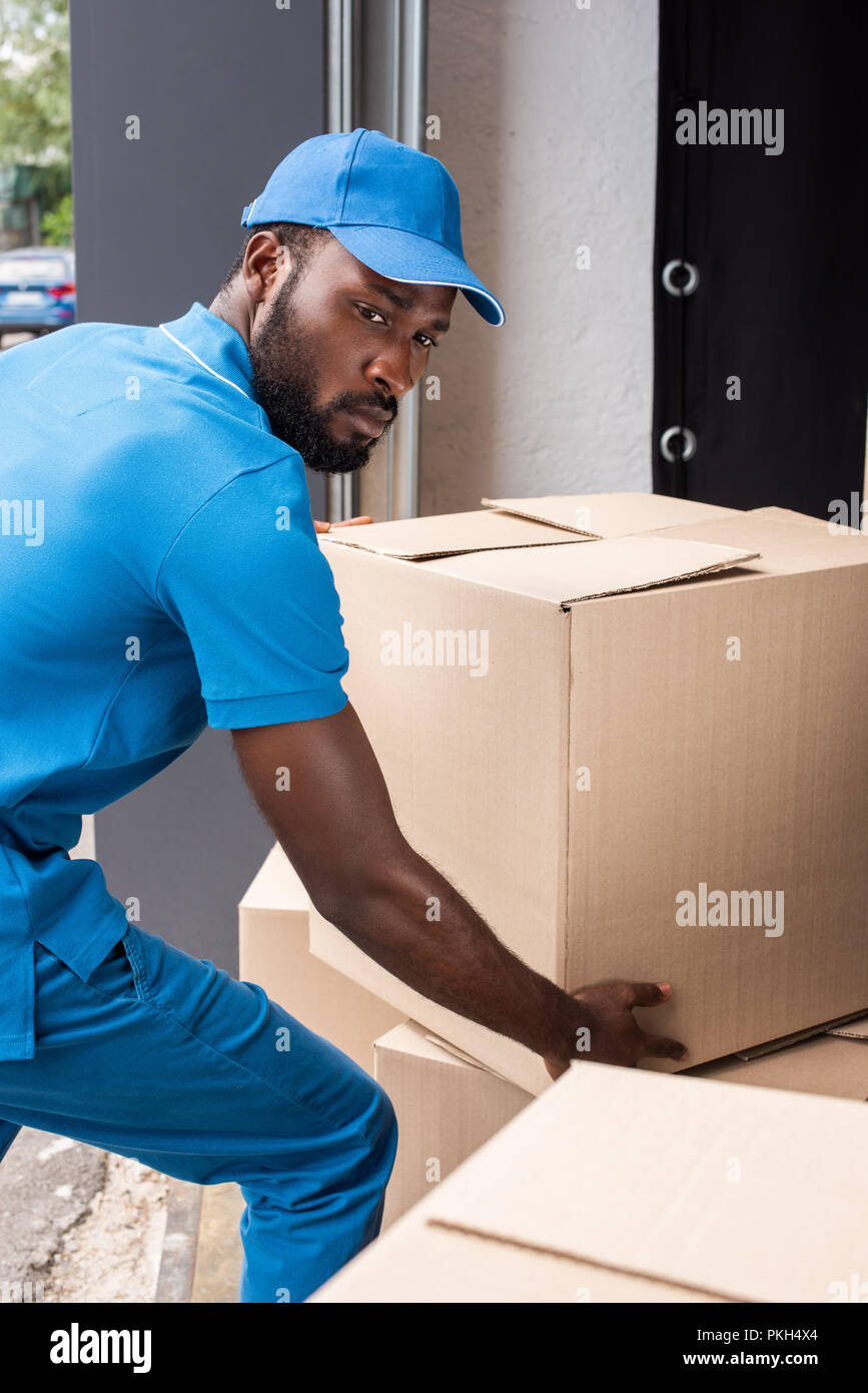 african american delivery man putting boxes on pile Stock Photo - Alamy