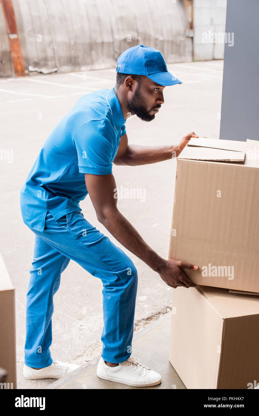 side view of african american delivery man putting boxes on pile Stock ...