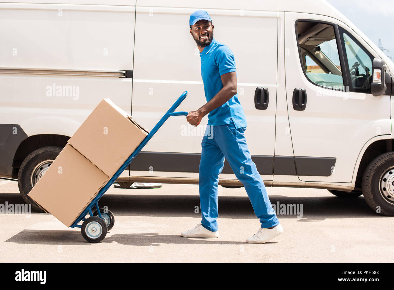 side view of african american delivery man with cart and boxes Stock ...