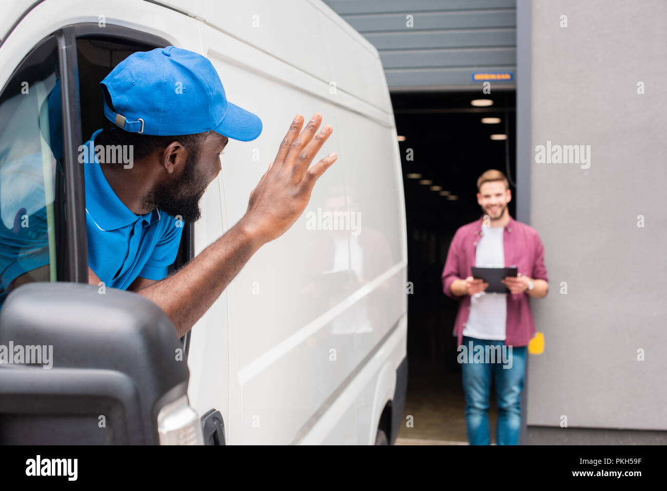 african american courier waving hand to client Stock Photo - Alamy