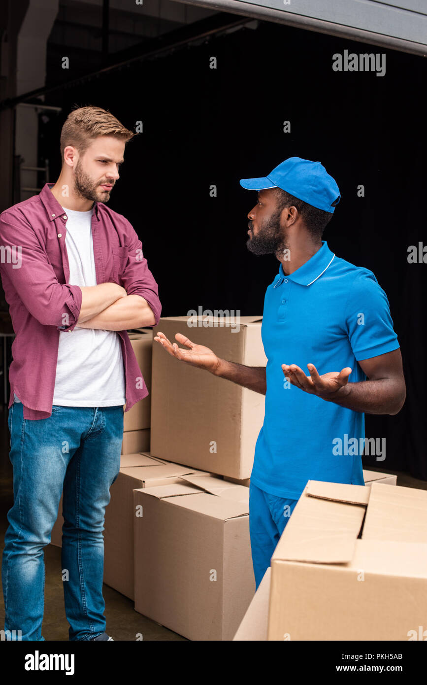 caucasian client with crossed arms looking at african american courier ...