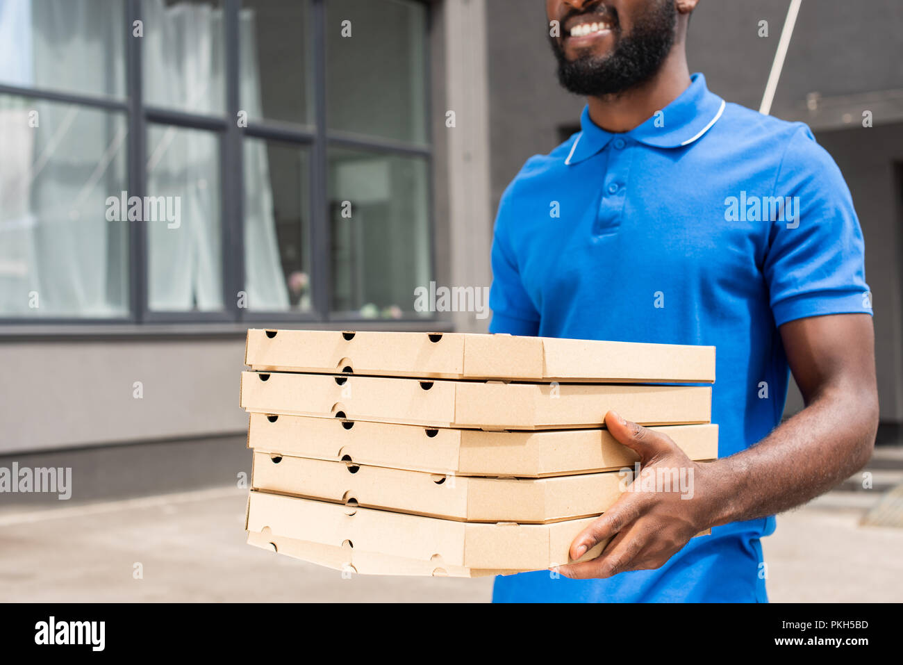 cropped image of african american delivery man carrying pizza boxes ...