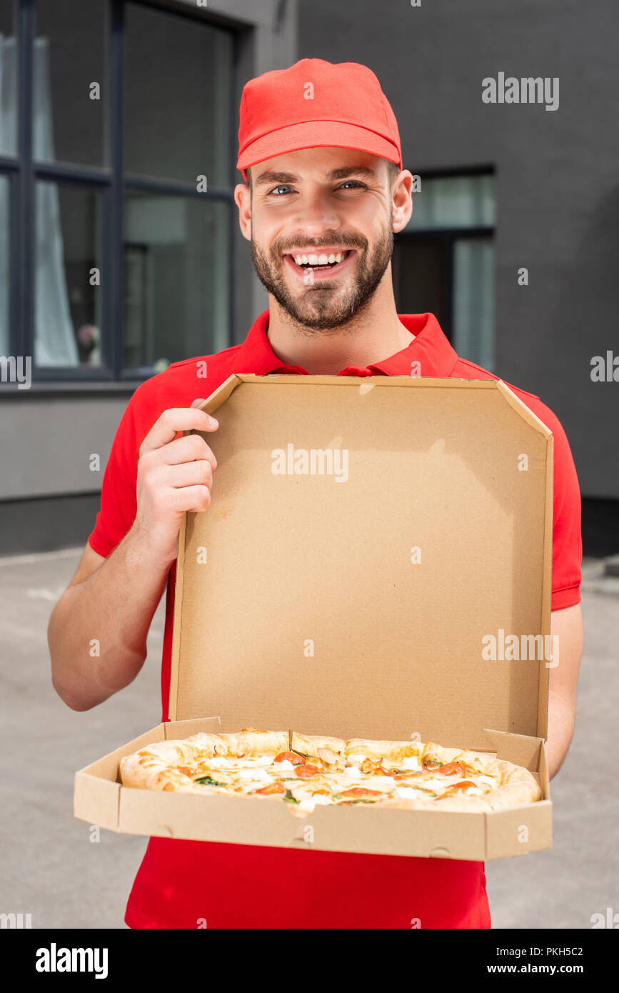 smiling caucasian delivery man holding box with pizza Stock Photo - Alamy