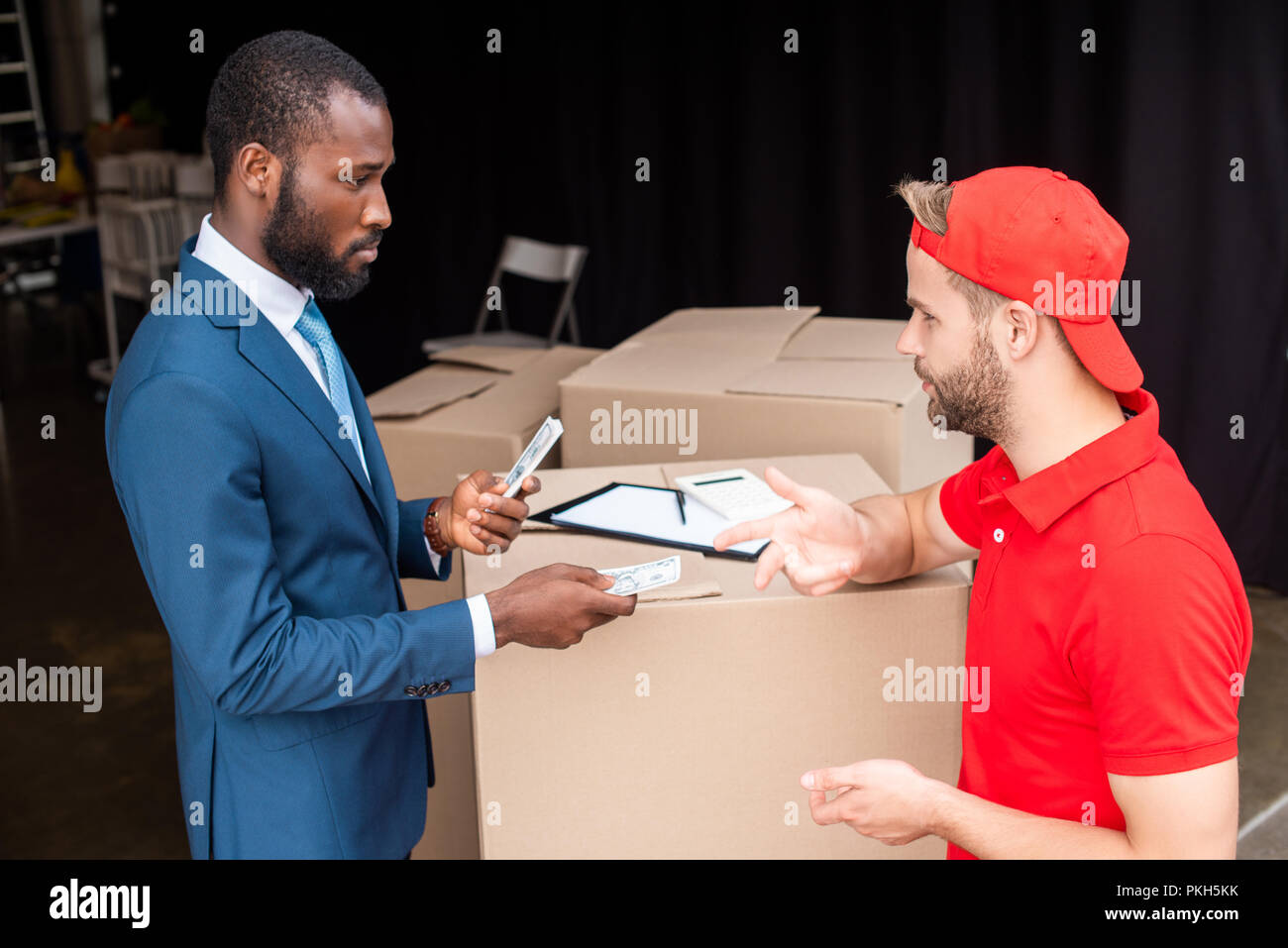 side view of african american client paying for delivery with cash ...