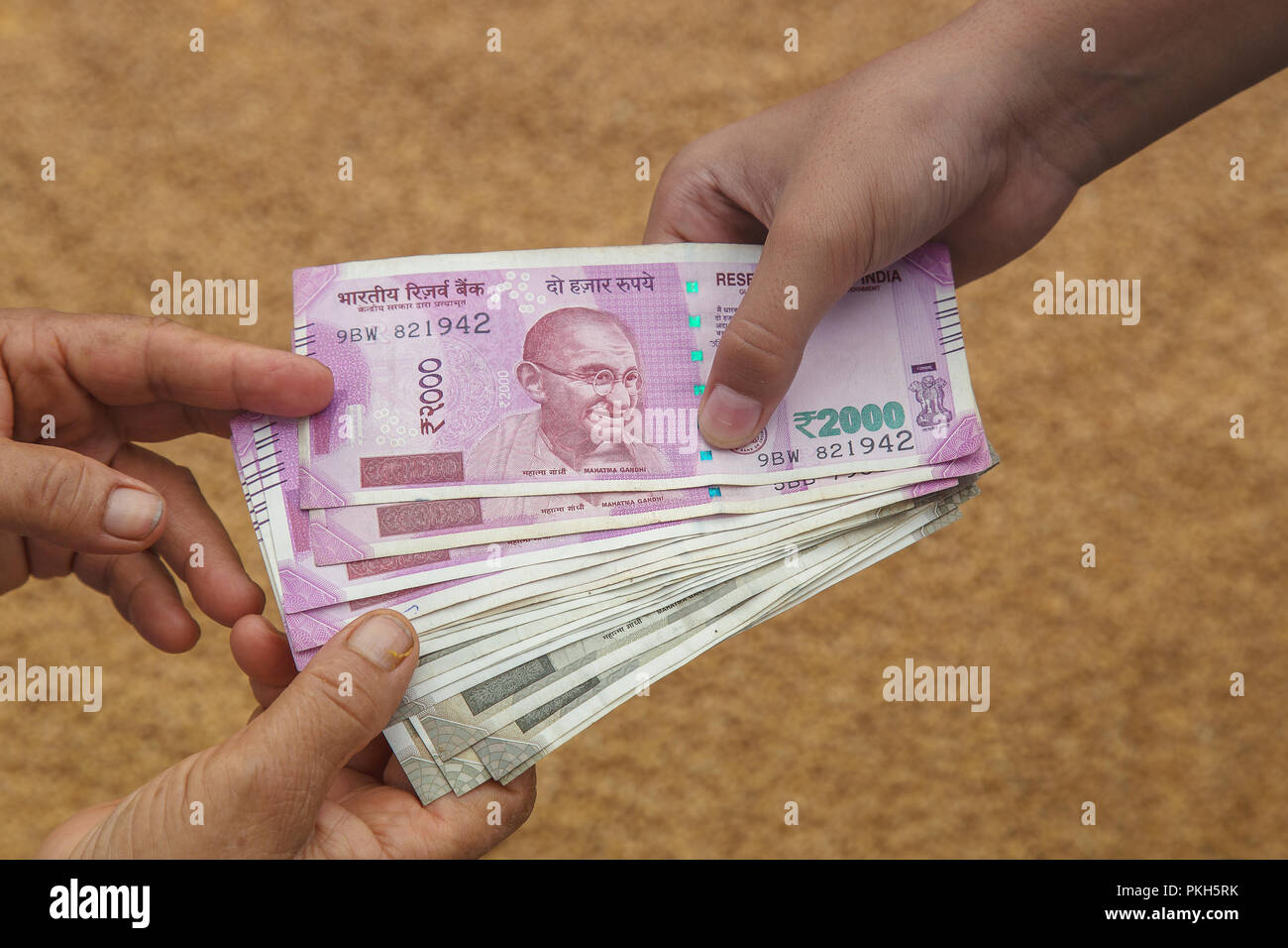 Hand Giving Indian 500 and 2000 Rupee Bank Notes over wheat background ...