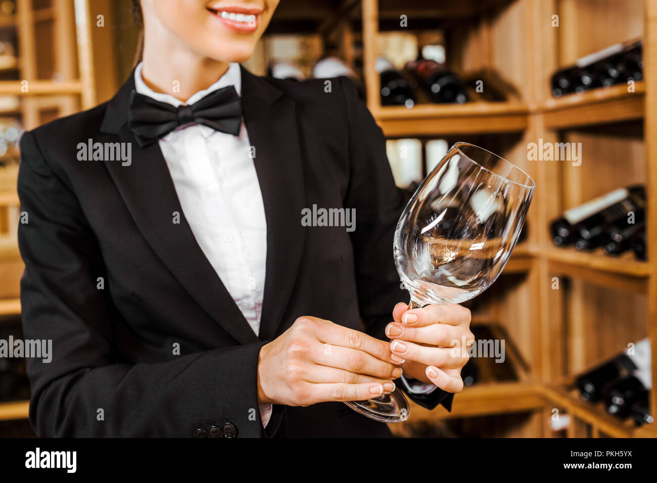 cropped shot of female wine steward with clean glass at wine store ...