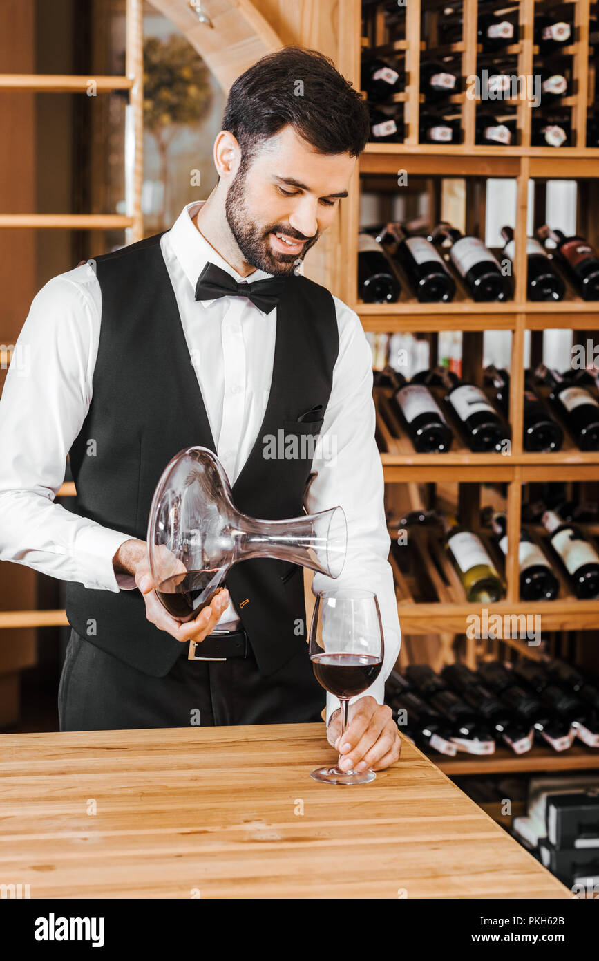 handsome young sommelier pouring wine from decanter at wine store Stock ...