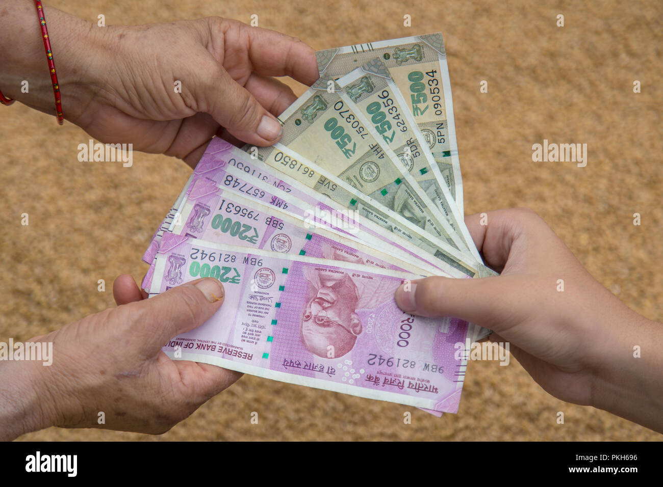 Hand Giving Indian 500 and 2000 Rupee Bank Notes over wheat background ...