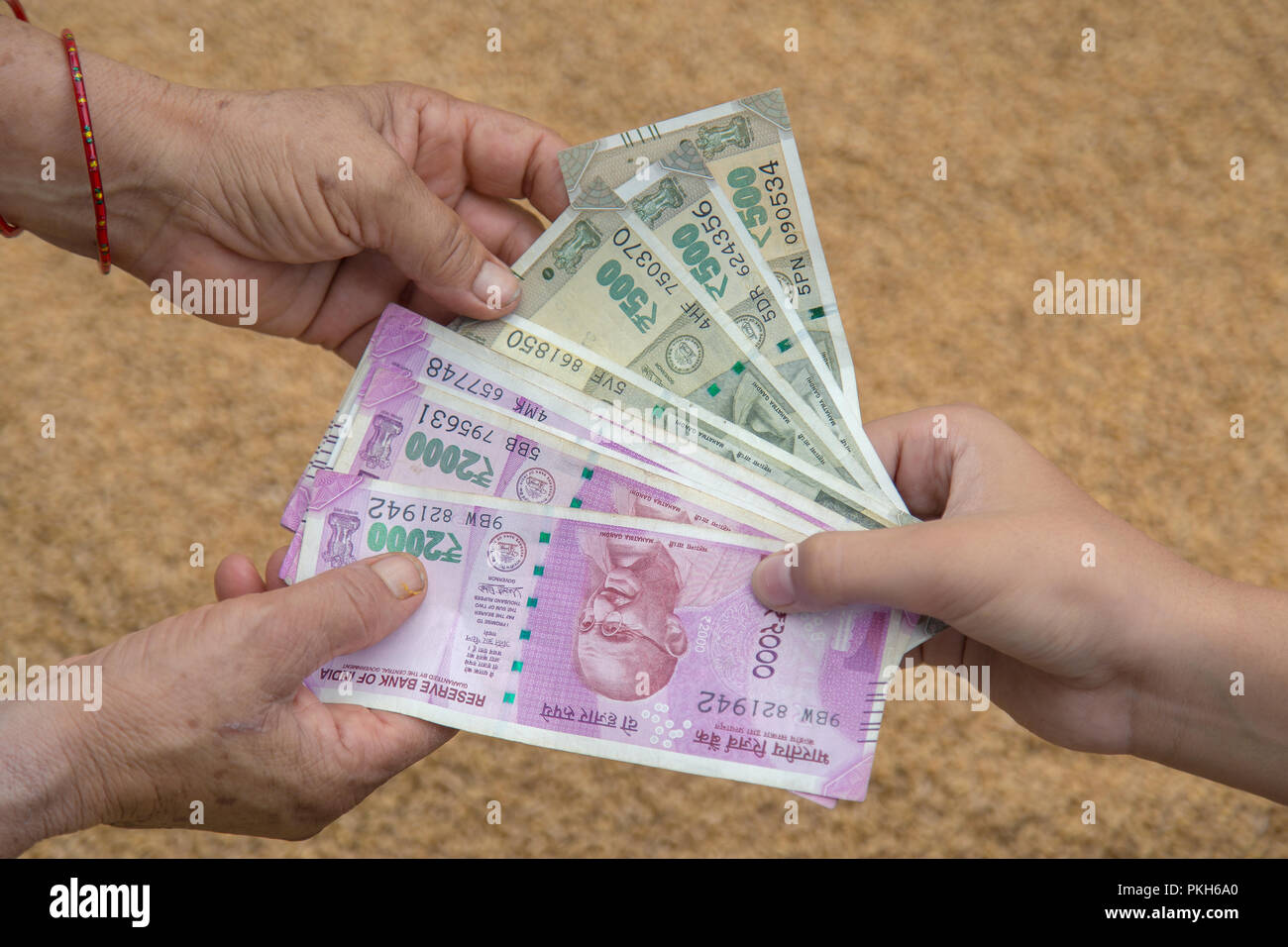 Hand Giving Indian 500 and 2000 Rupee Bank Notes over wheat background ...