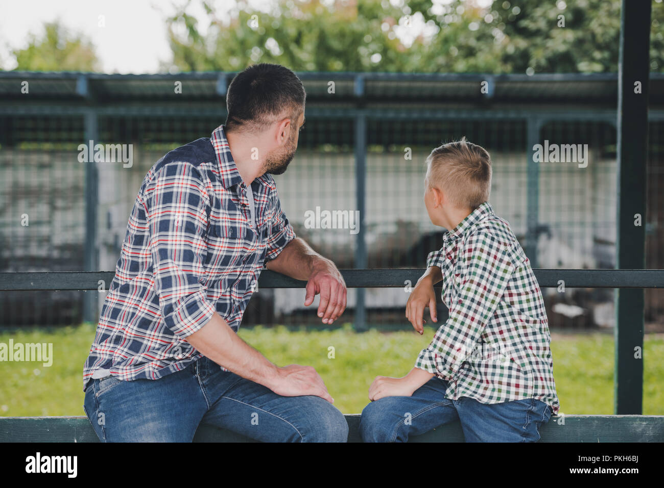 side view of father and son in checkered shirts sitting together and ...