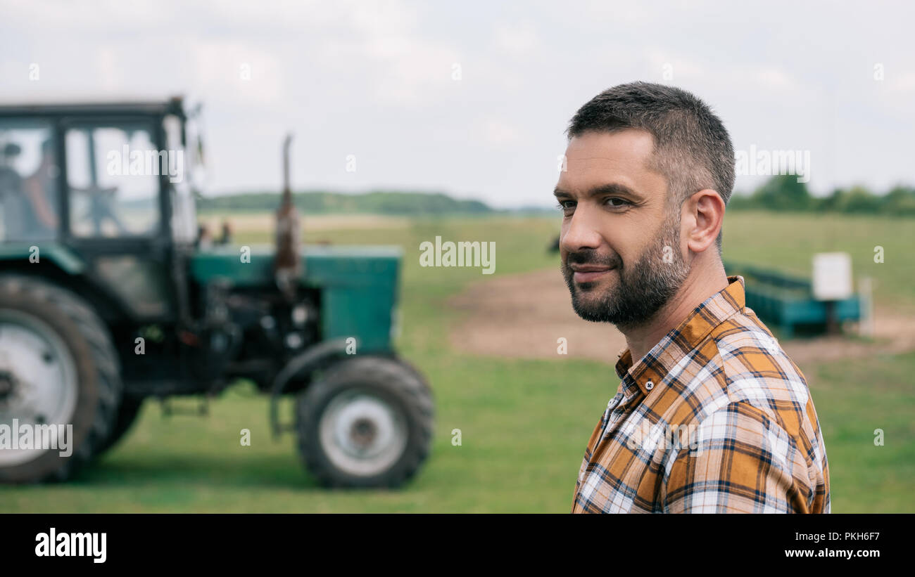 side view of handsome middle aged farmer smiling while standing near ...
