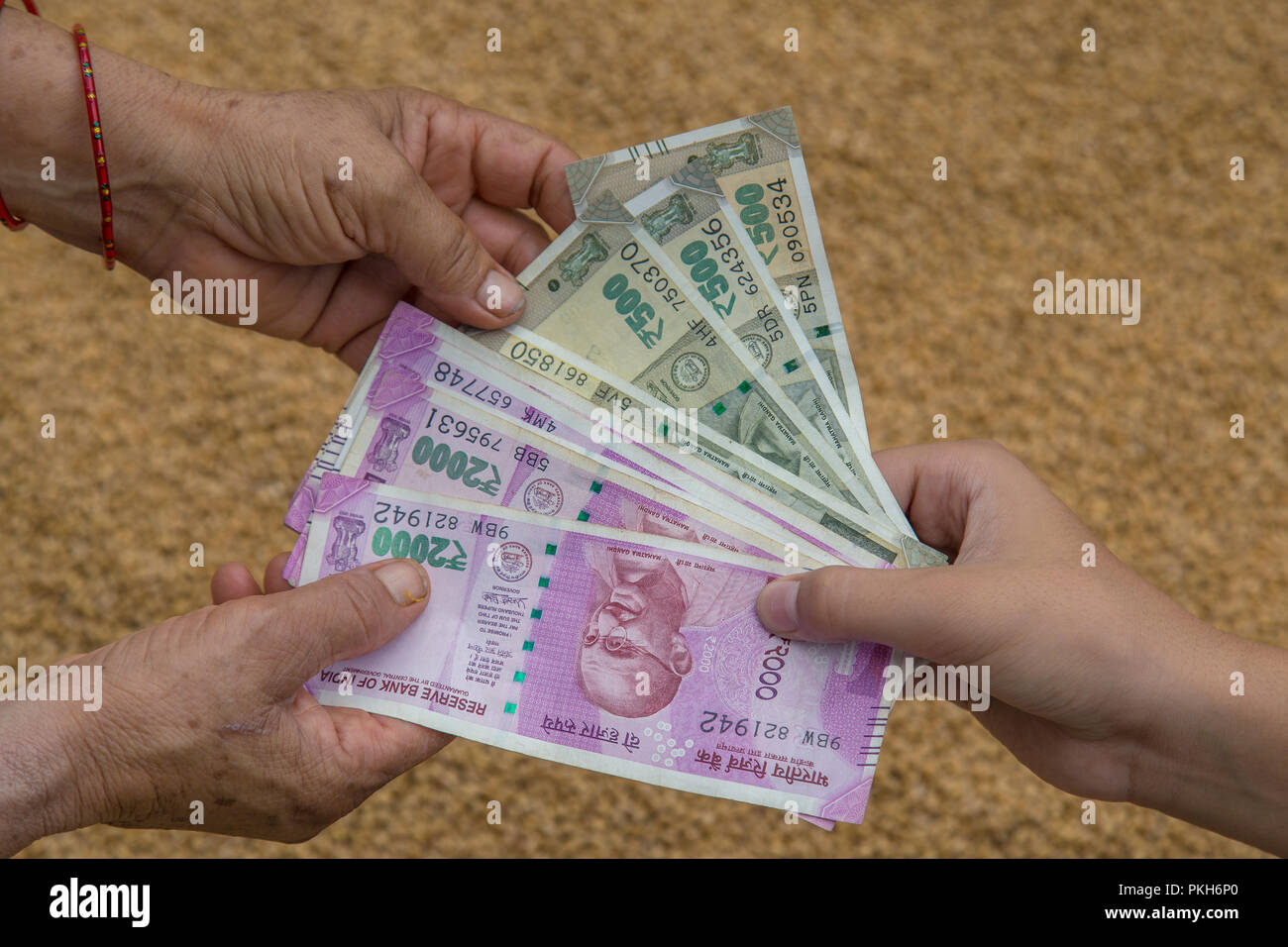 Hand Giving Indian 500 and 2000 Rupee Bank Notes over wheat background ...