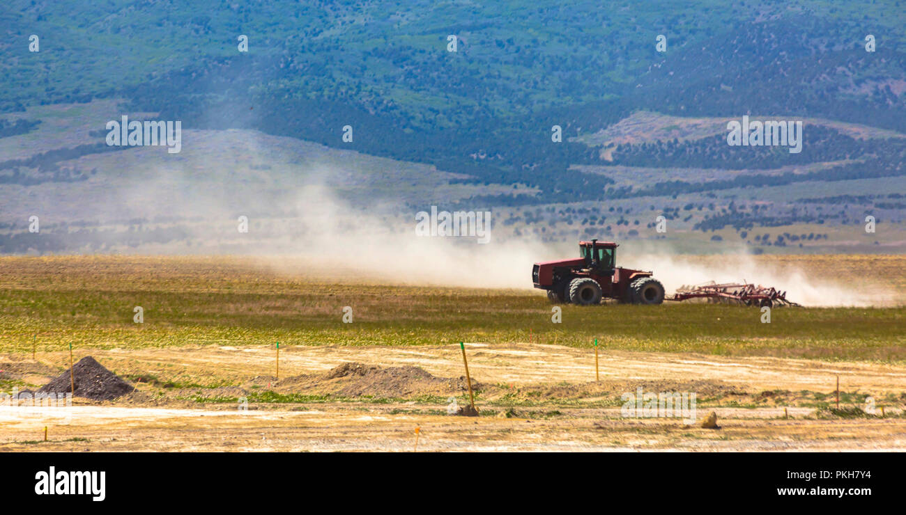 Red tractor with large wheels on a field in Utah Stock Photo - Alamy