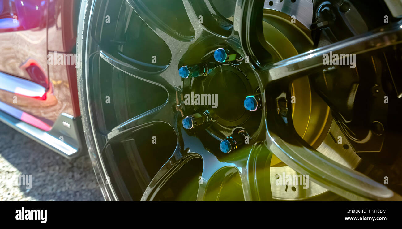 Shiny mag wheel of a red car with blue bolts Stock Photo - Alamy