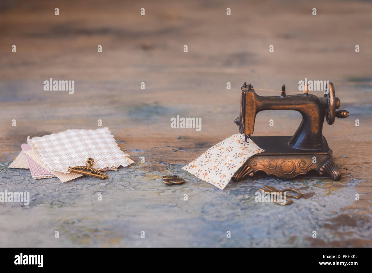 Vintage mini sewing machine with scissors, buttons and fabric on rustic ...