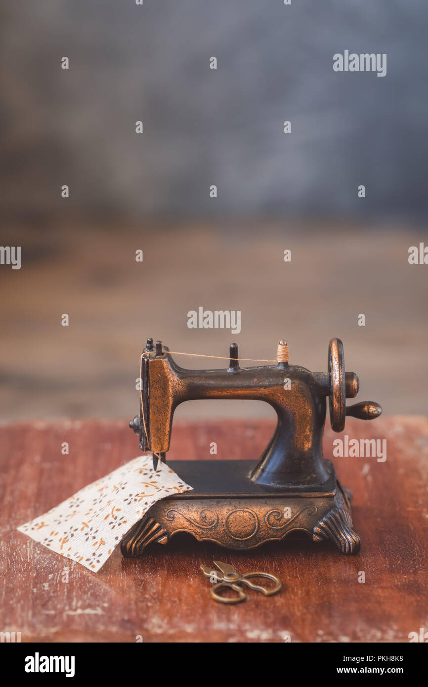 Vintage mini sewing machine with scissors, buttons and fabric on rustic ...