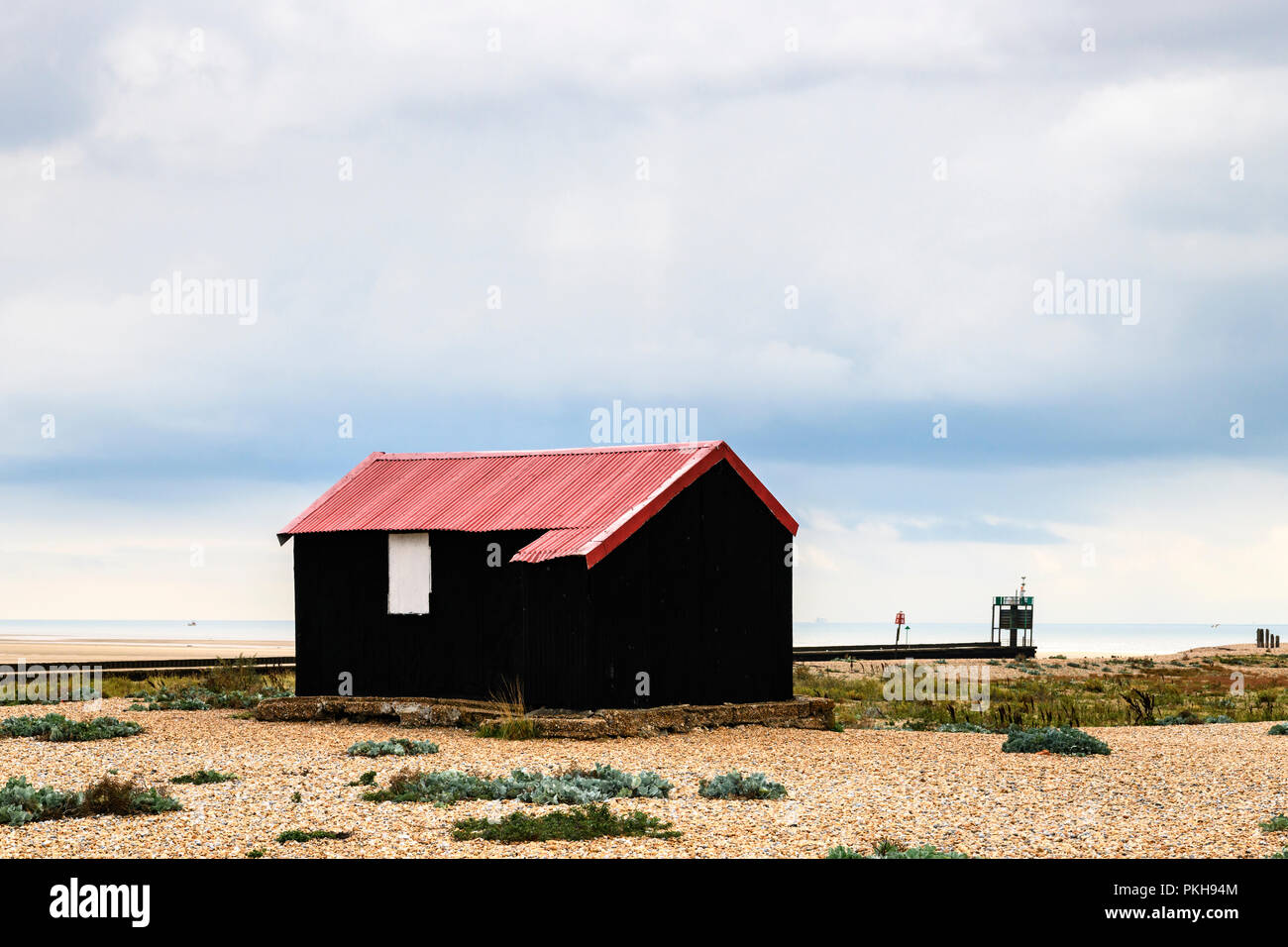 Gran's Hut. A corrugated black and red hut on a shingle beach at Rye ...