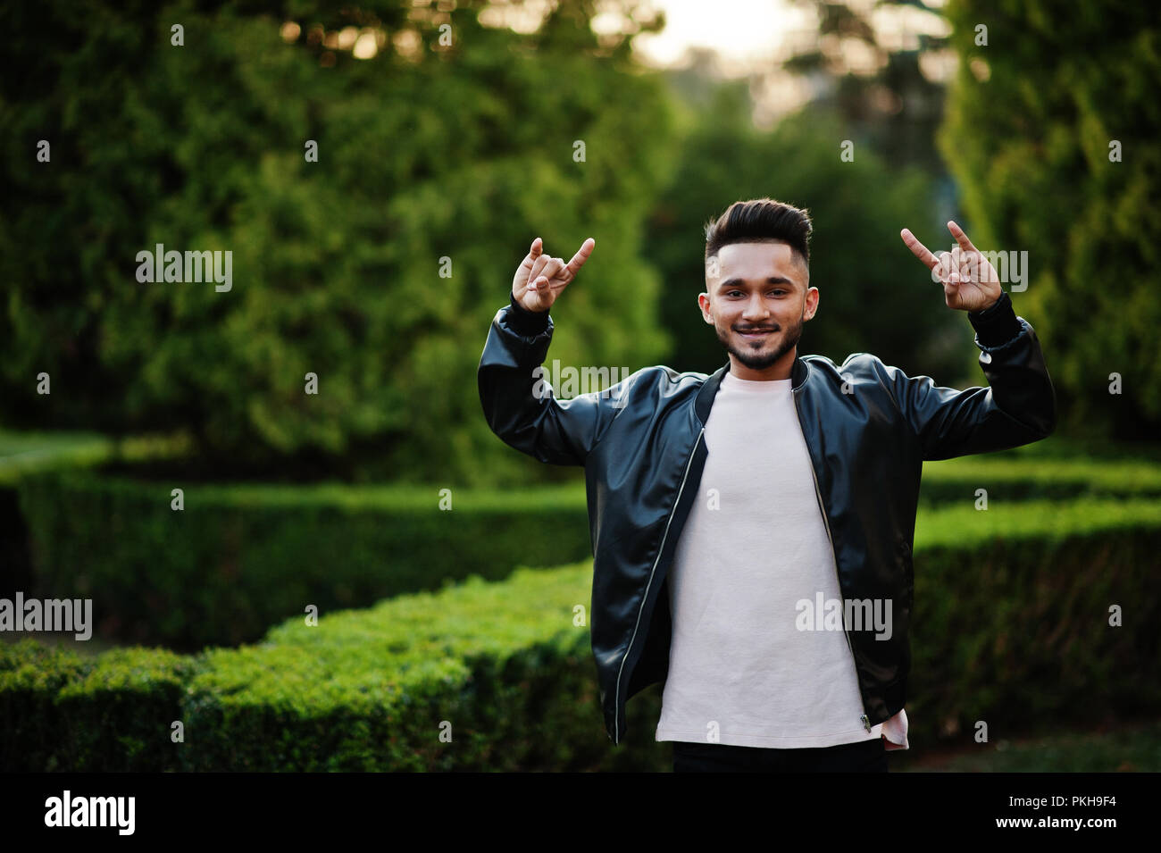 Stylish indian beard man at black leather jacket shows rock fingers ...