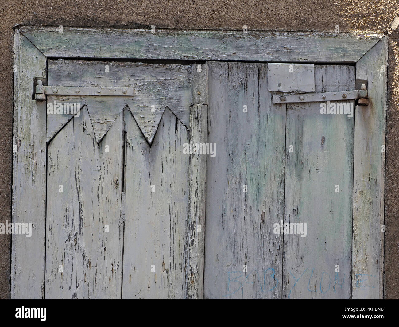 shades of grey in dilapidated repaired window shutters in worn down ...