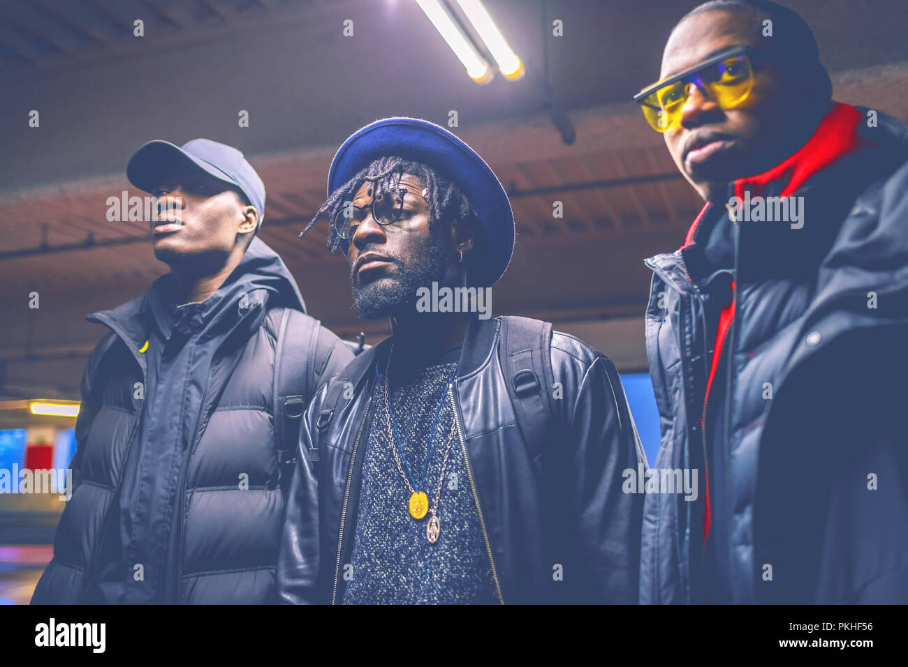 portrait three young black men posing in a parking lot looking away ...